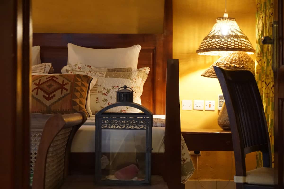 Quarto com cama, mesa de cabeceira, luminária e cadeira.