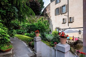 Um jardim com vasos de plantas e um espaço de pátio com mobiliário para área externa.