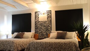 Quarto de hotel com duas camas, um ornamento na parede com padrão de zebra e uma planta em vaso.