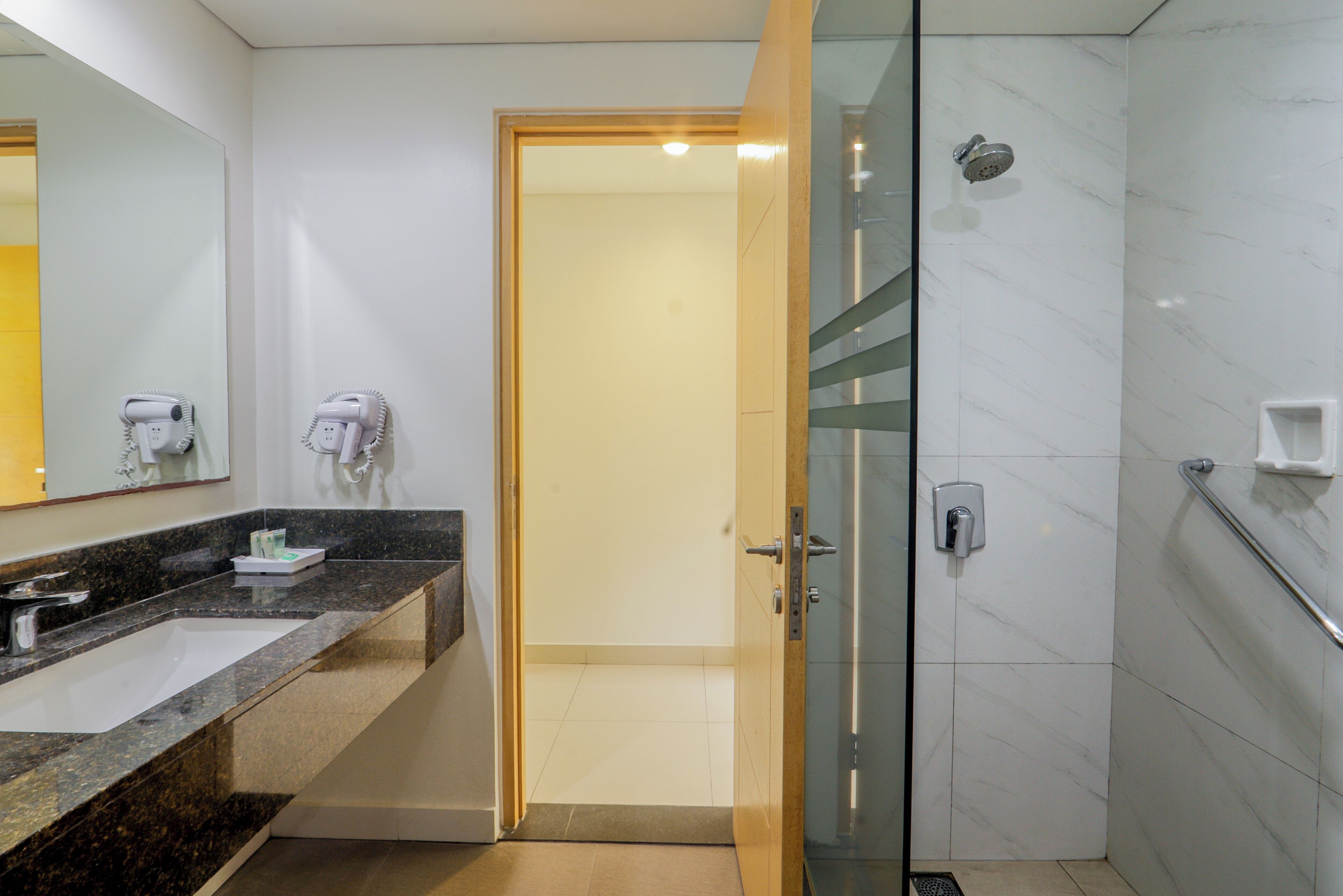 Casa de banho moderna com chuveiro de mármore, cabine de hidromassagem com vidro e toucador com lavatório e aquecedor de toalhas.