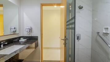Casa de banho moderna com chuveiro de mármore, cabine de hidromassagem com vidro e toucador com lavatório e aquecedor de toalhas.