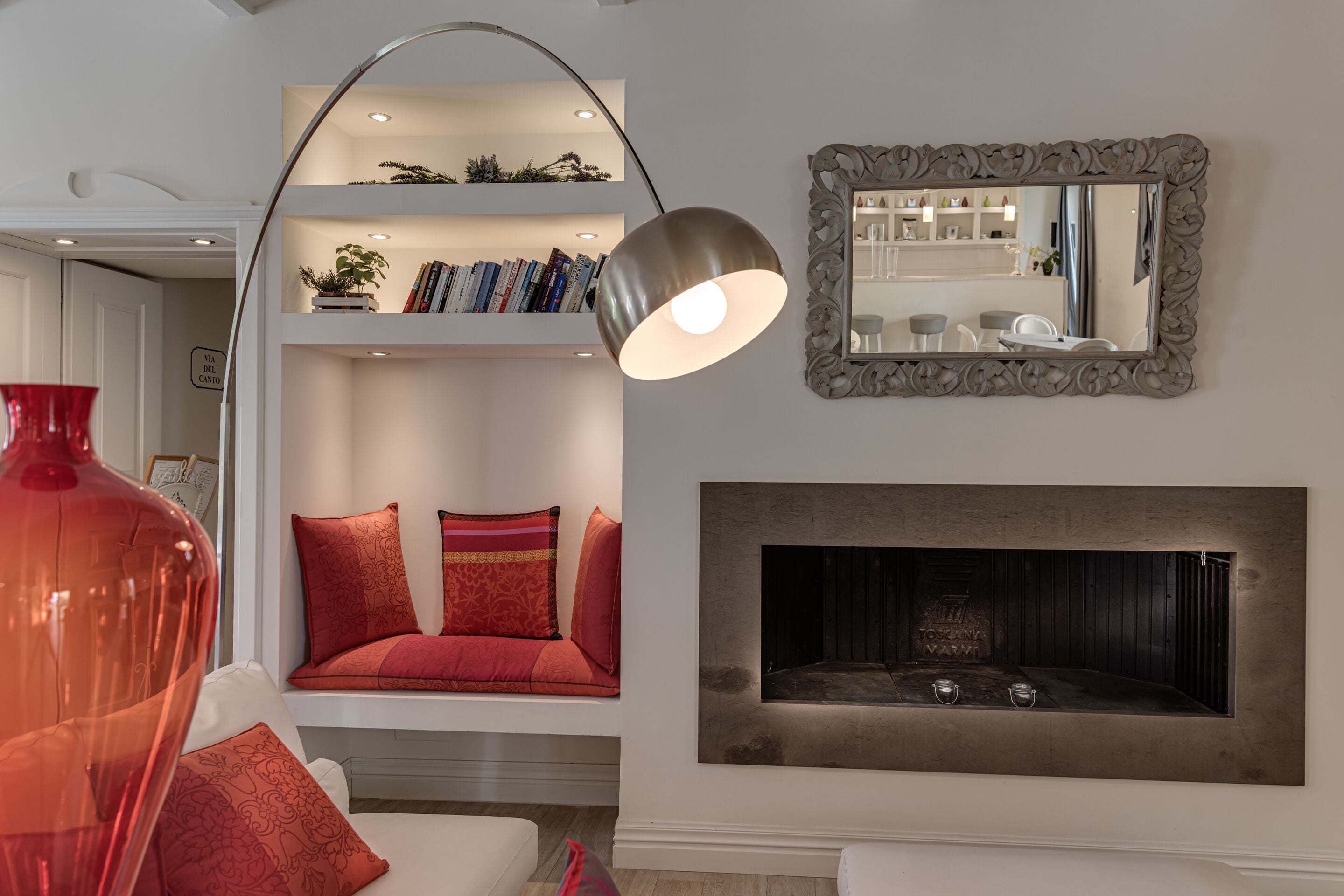 Uma sala de estar moderna com lareira, estante e sofá vermelho.
