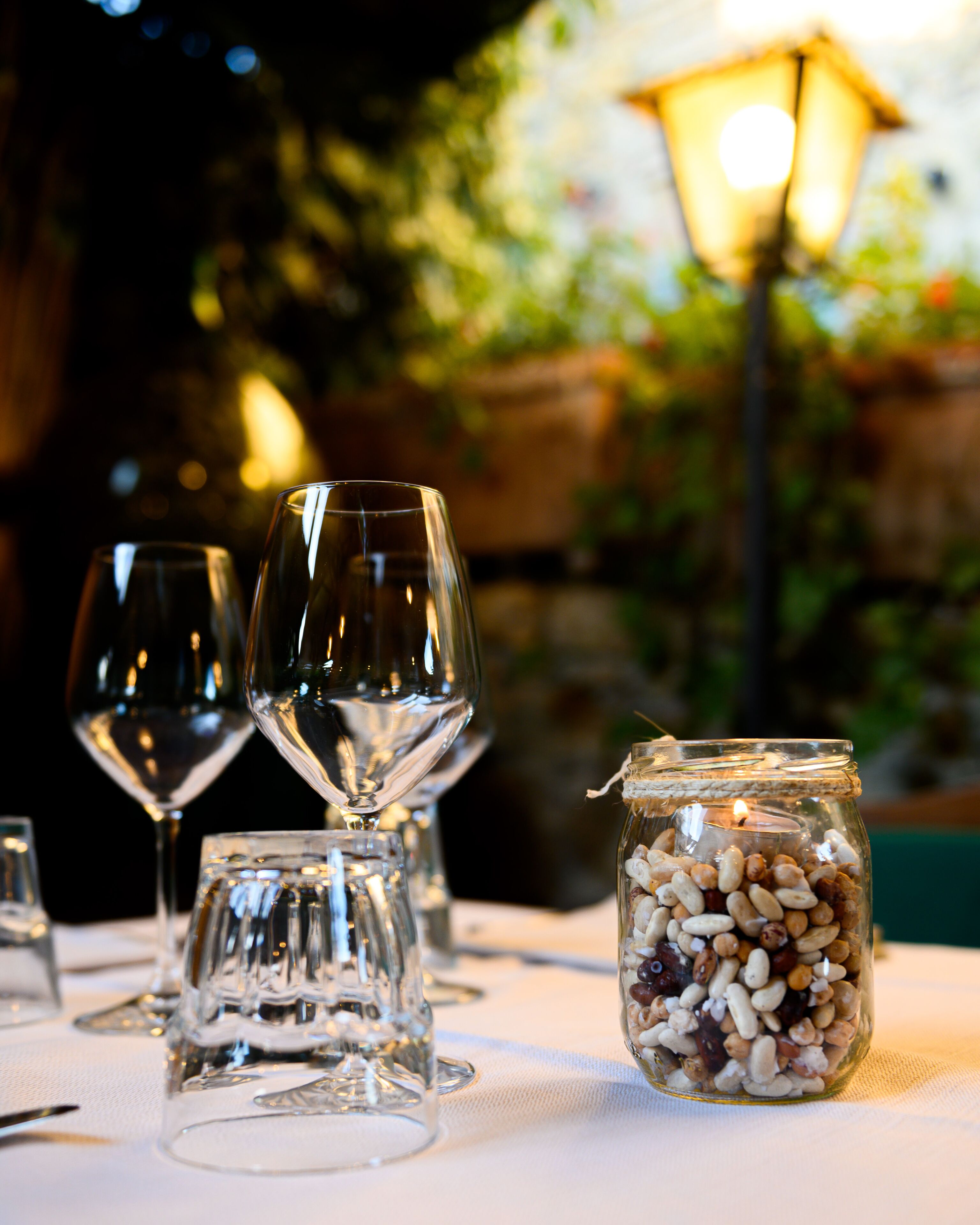 Uma mesa com copos de vinho e um pote de nozes.