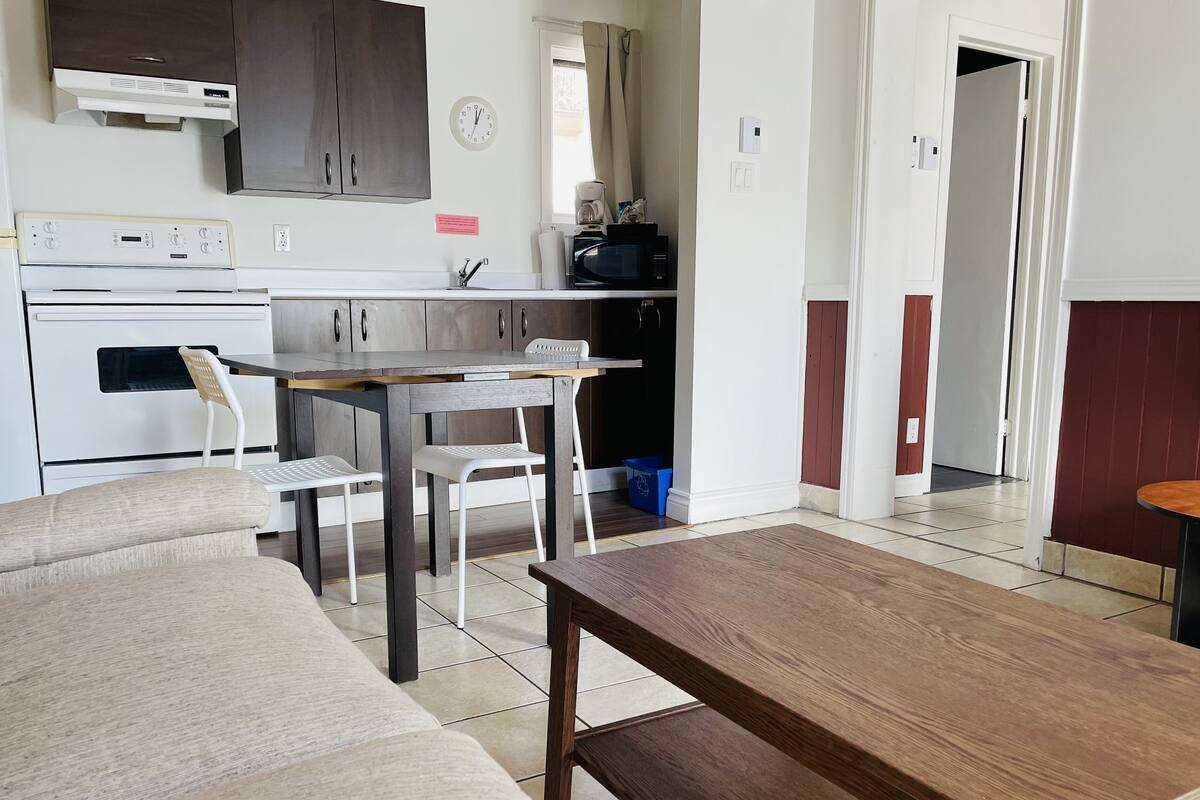 Uma cozinha moderna com armários escuros, uma mesa de jantar de madeira e um sofá branco.