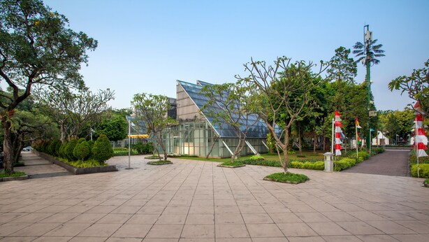 Uma praça ampla com um edifício moderno, fachada de vidro e design de telhado geométrico.