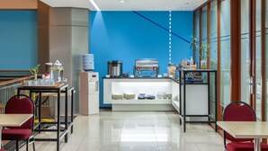Um café moderno com uma parede azul decorativa, uma estação de café e áreas de estar.