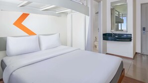 Quarto de hotel moderno com beliche, banheiro com pia e espelho, e uma janela grande.