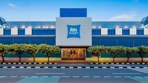Um edifício moderno com uma placa de destaque 'ibis budget', uma entrada convidativa e uma fachada estruturada com telhado plano.