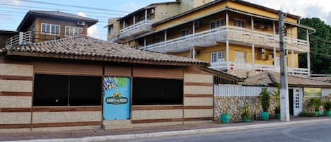 Um edifício com telhado de telhas, uma placa e uma parede de pedra.