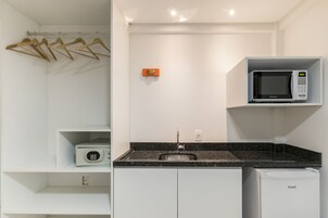 Uma cozinha compacta com micro-ondas, pia e geladeira pequena.