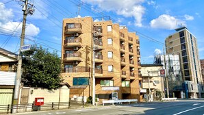 Um edifício residencial de vários andares com varandas, uma rua em frente e uma placa de proibido estacionar.