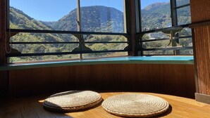 Quarto com uma grande janela que oferece vista para uma paisagem montanhosa.