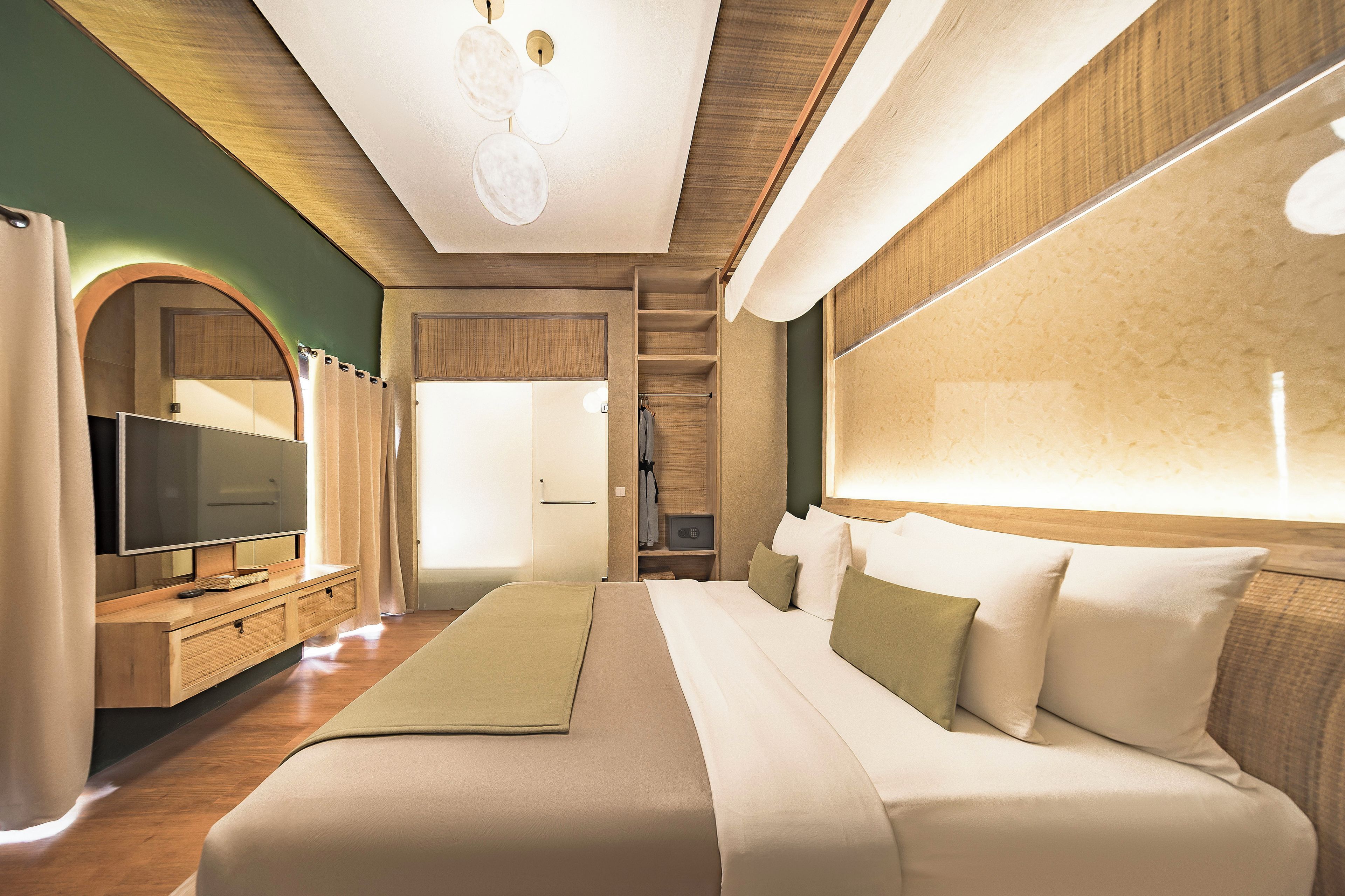 Quarto de hotel moderno com uma cama grande, televisão e guarda-roupa.