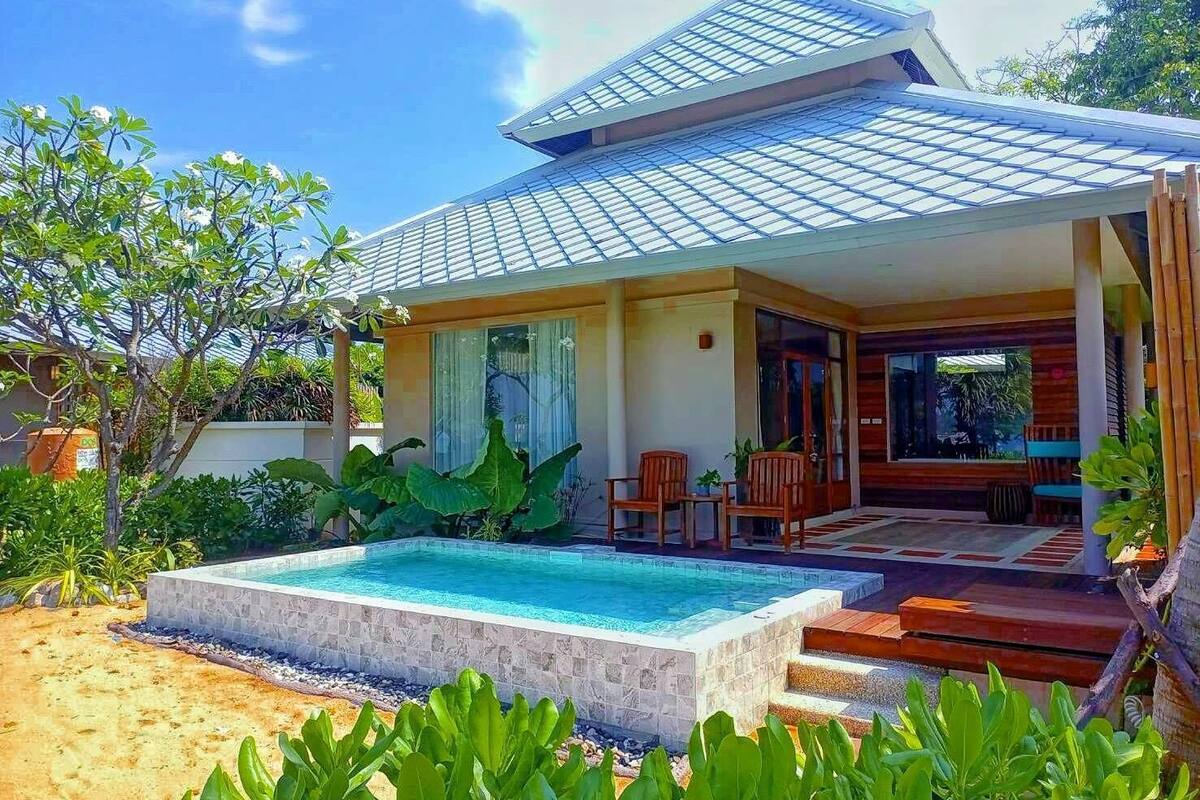 Uma casa moderna com piscina, deck de madeira e plantas tropicais.