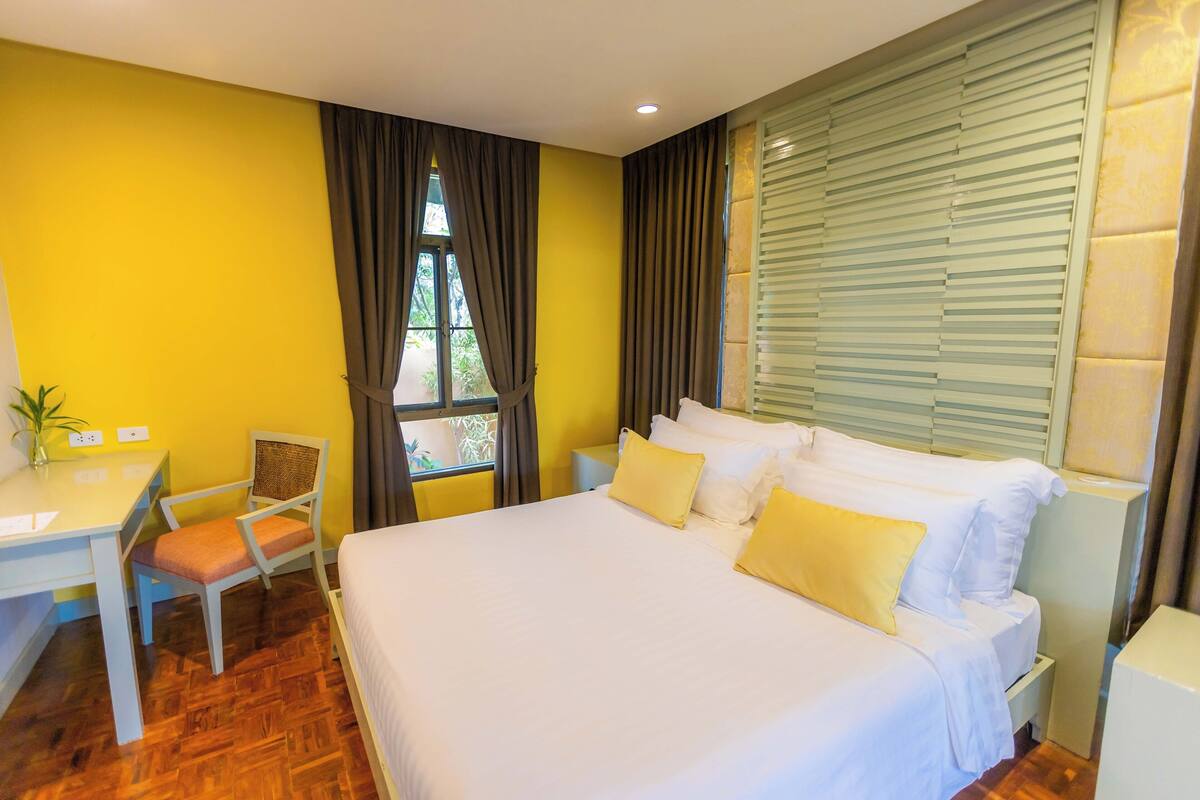 Quarto de hotel com cama, escrivaninha e cadeira.