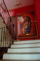 Uma escadaria com corrimão, um quadro emoldurado na parede e uma porta no final.