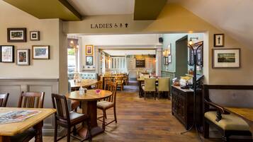 Um restaurante com móveis de madeira, uma placa com a inscrição 'LADIES' e quadros nas paredes.