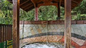 Área de águas termais com piso em mosaico e vigas de madeira.