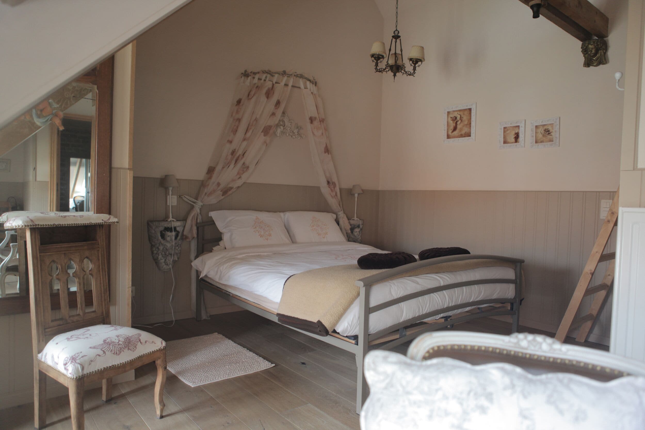 Um quarto com cama, mesa de cabeceira, cadeira, armário de madeira, espelho e lustre.