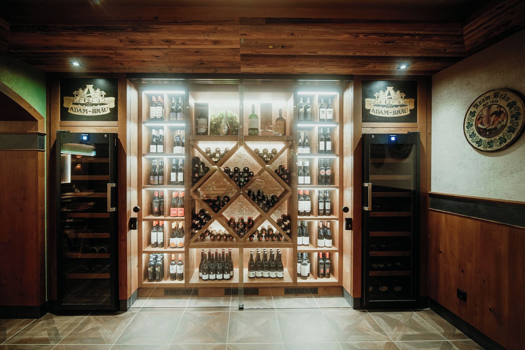 Uma adega de vinhos com prateleiras de madeira e uma vitrine em formato de diamante.