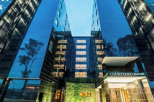 Um hotel moderno com fachada de vidro, um jardim vertical verde e a placa Courtyard Marriott.