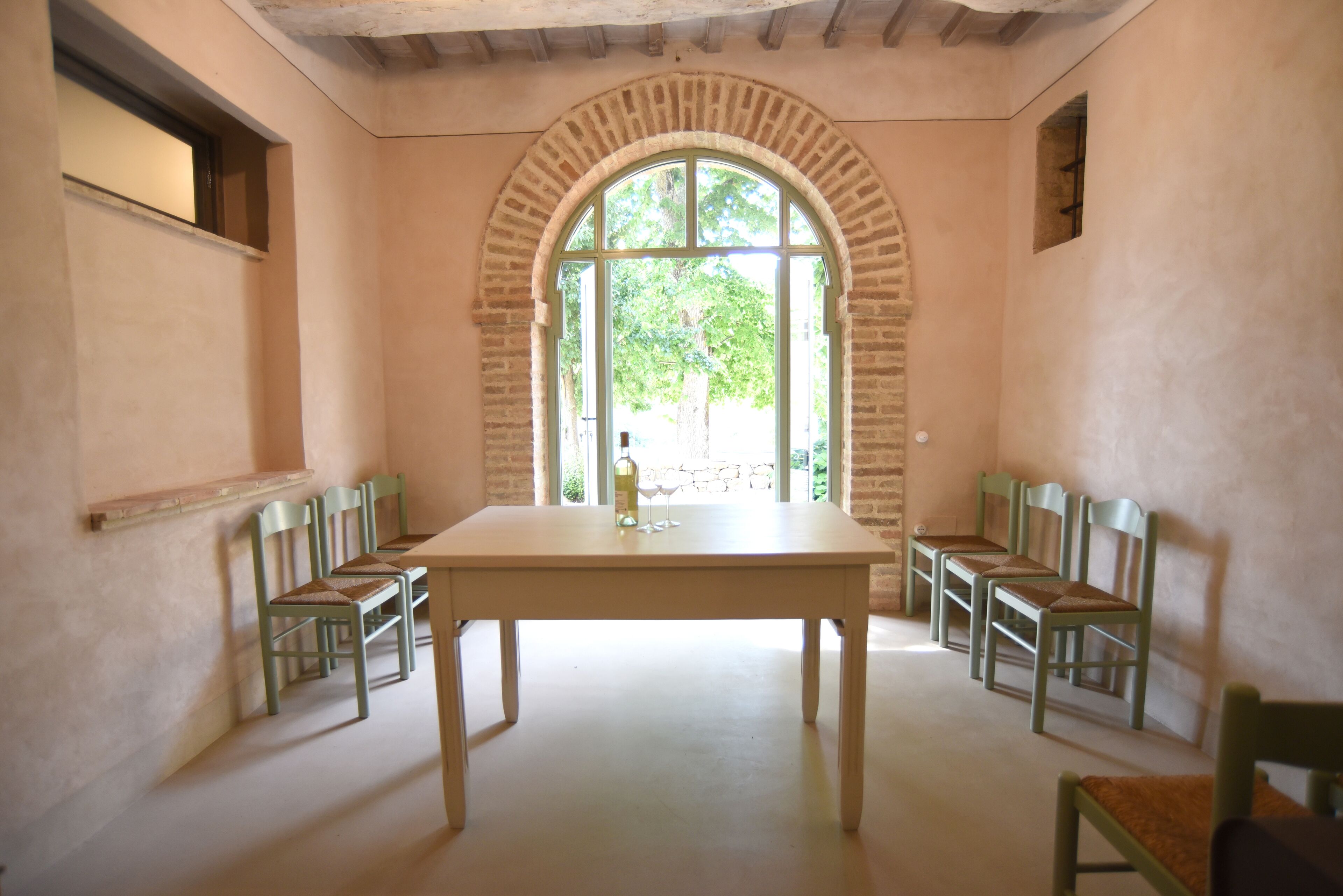 Um quarto com uma grande janela em arco, uma mesa e seis cadeiras.