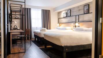 Quarto de hotel com duas camas, uma escrivaninha e uma cadeira.