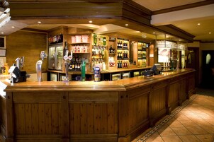 Uma área de bar com painéis de madeira, prateleiras cheias de garrafas e um caixa registradora.