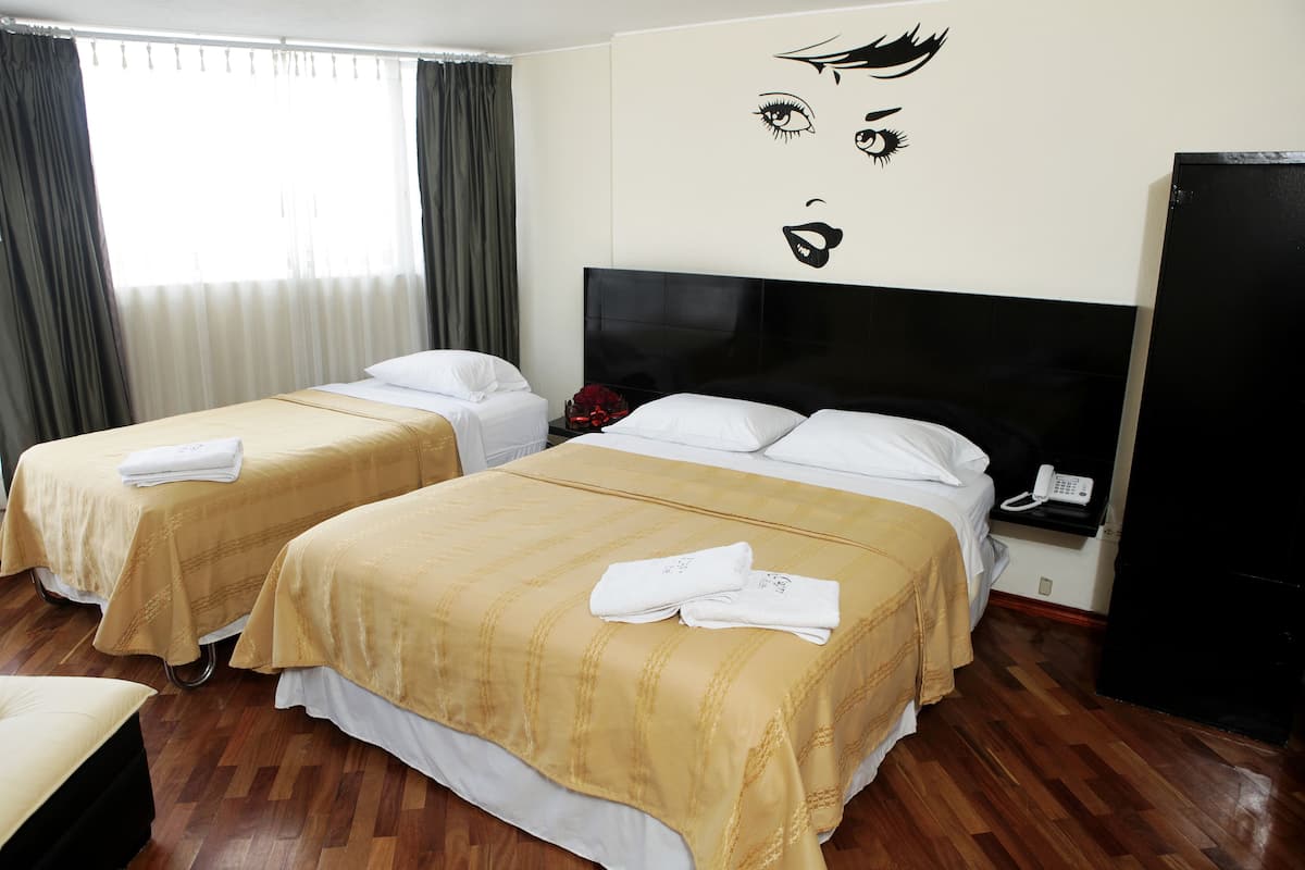 Quarto de hotel com duas camas, um espelho grande e um telefone fixado na parede.