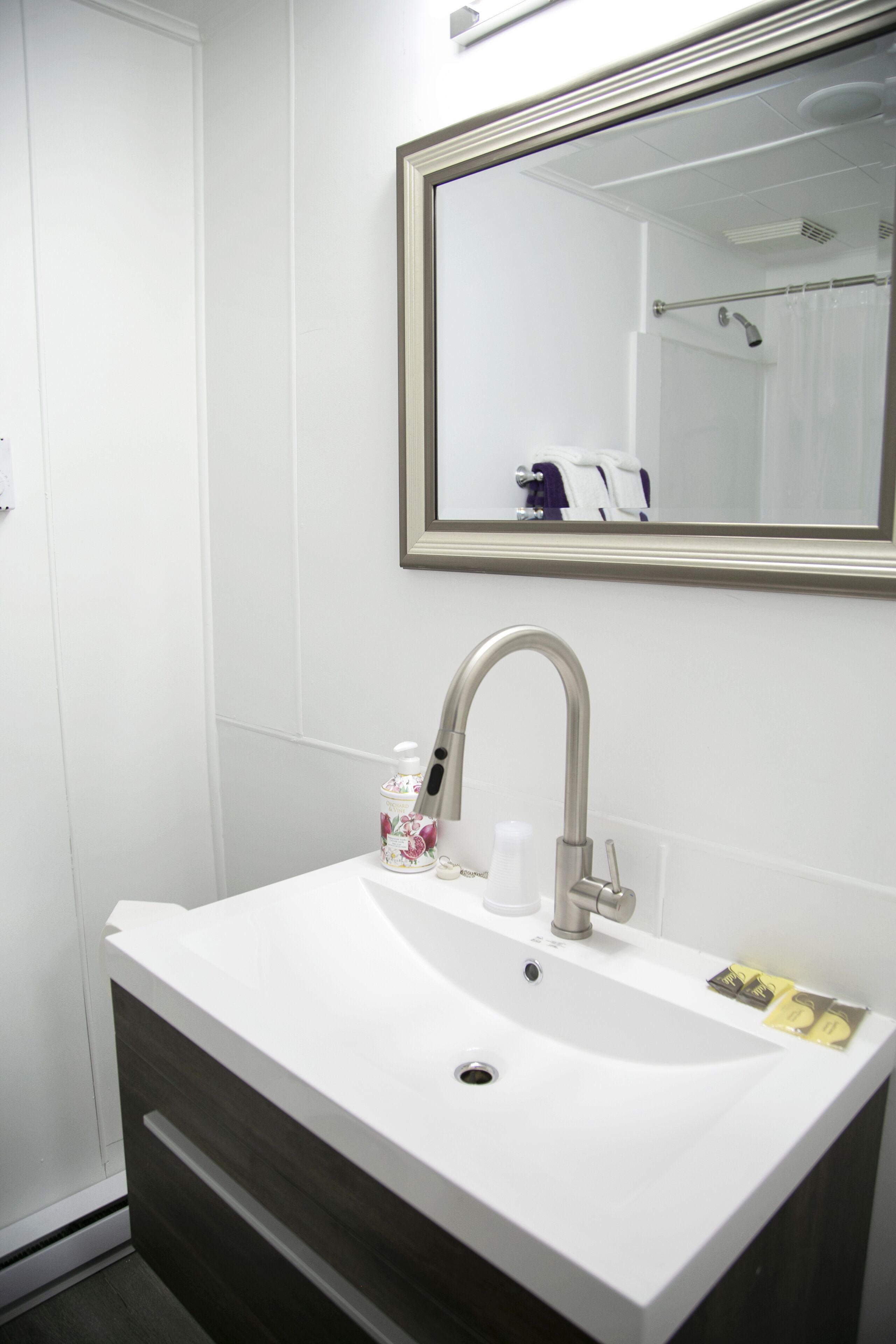 Casa de banho com lavatório branco, espelho e porta-toalhas.