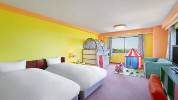 Quarto de hotel com duas camas, televisão, escrivaninha, janela com vista e um túnel de brincadeira.