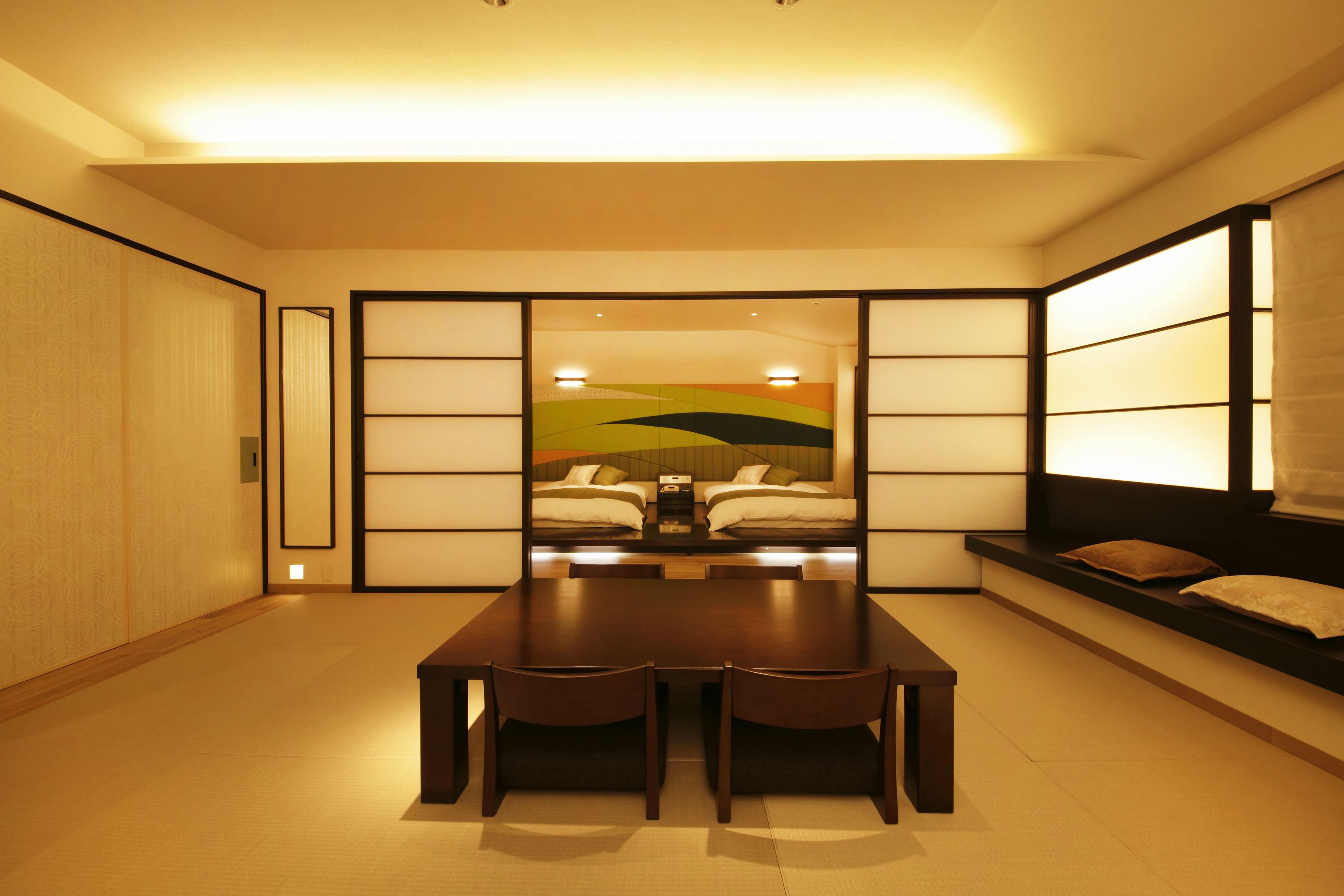Um quarto japonês tradicional, com tatames, uma mesa baixa e cadeiras, e um futon.