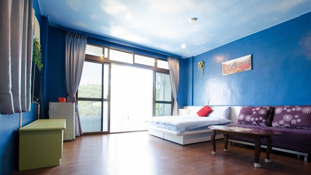Quarto moderno com uma janela ampla, uma cama, um sofá e uma pequena mesa.