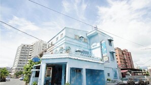 Um edifício de dois andares com fachada azul e uma varanda.
