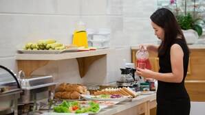 Disposição de buffet com diversos alimentos e uma pessoa servindo bebida.