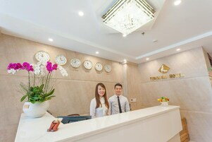Uma receção com um relógio, uma planta e um letreiro para o HOTEL THIEN KAI.