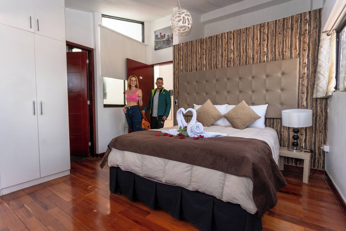 Quarto com uma cama grande, cabeceira de madeira, luminária de cabeceira e um guarda-roupa.