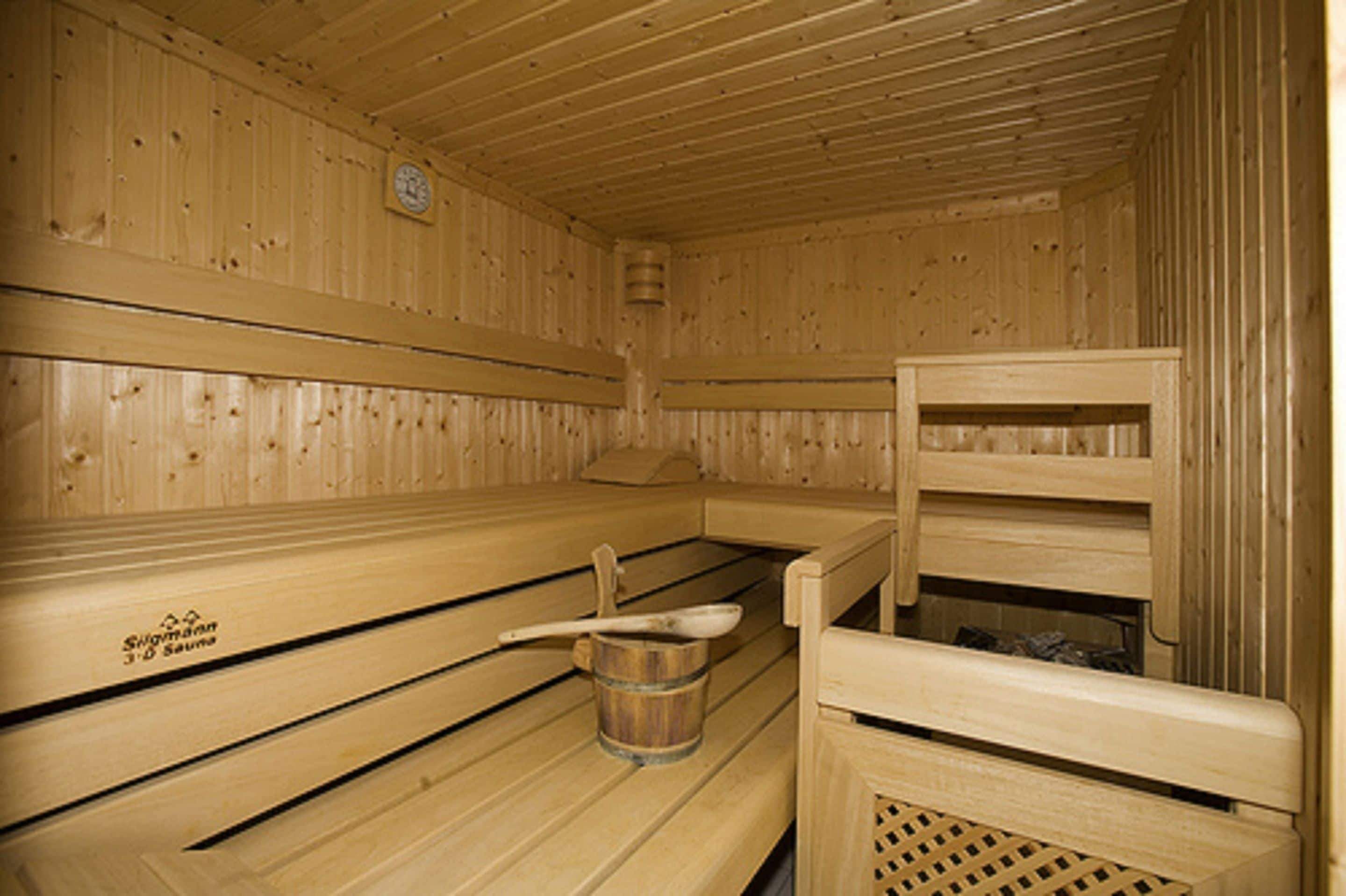 Uma sauna com bancos de madeira e um balde de madeira com uma concha.