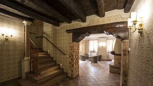 Uma escadaria leva a um quarto com papel de parede estampado e piso de azulejos.
