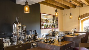 Uma área de bar com uma máquina de café, copos de vinho e garrafas nas prateleiras.
