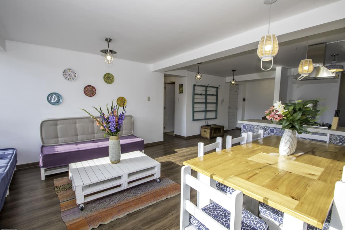 Uma sala de estar moderna com uma mesa de jantar de madeira, cadeiras brancas, um sofá e uma mesa de centro.