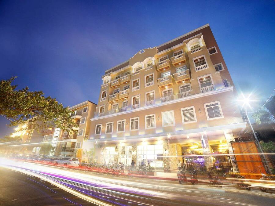 Hotel com vários andares, varandas, restaurante no térreo e fachada bem iluminada.