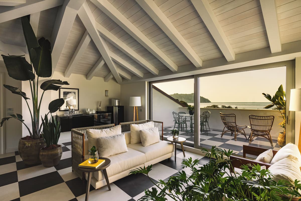 Uma sala de estar moderna com piso xadrez, um sofá e uma grande janela com vista para o mar.