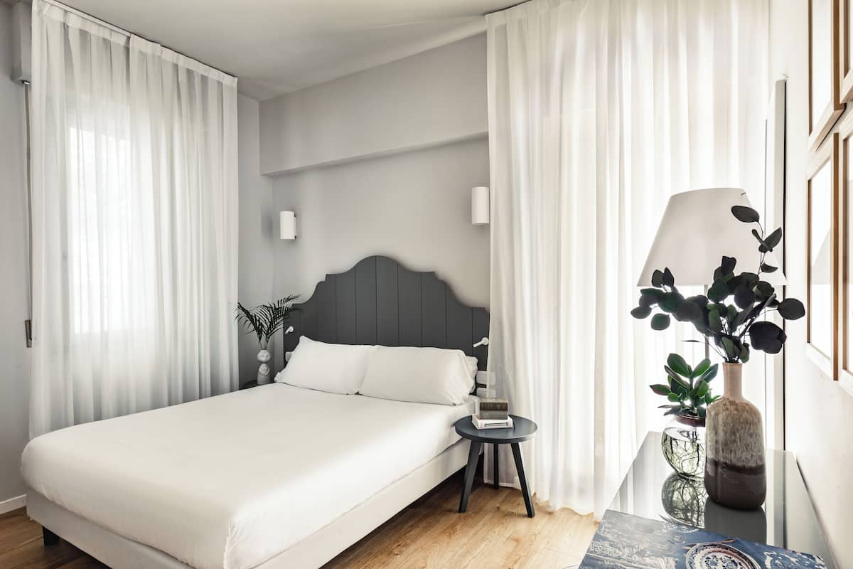 Quarto bem arrumado com cama, mesa de cabeceira e luminária.