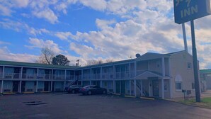Um motel com uma placa indicando 'Super 7 Inn', apresentando um edifício de dois andares com varandas e um estacionamento.