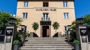 Um edifício de dois andares com uma placa na entrada que diz "Wilhelmsen House" e "WH café".