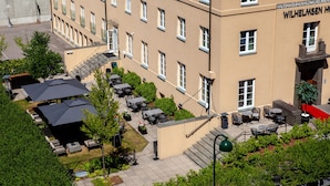 Um hotel com área externa para sentar, escadaria e entrada com tapete vermelho.