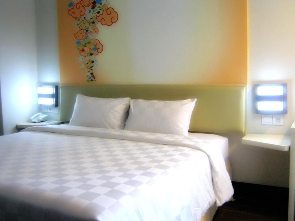 Quarto de hotel com cama, duas mesas de cabeceira e um ornamento na parede.