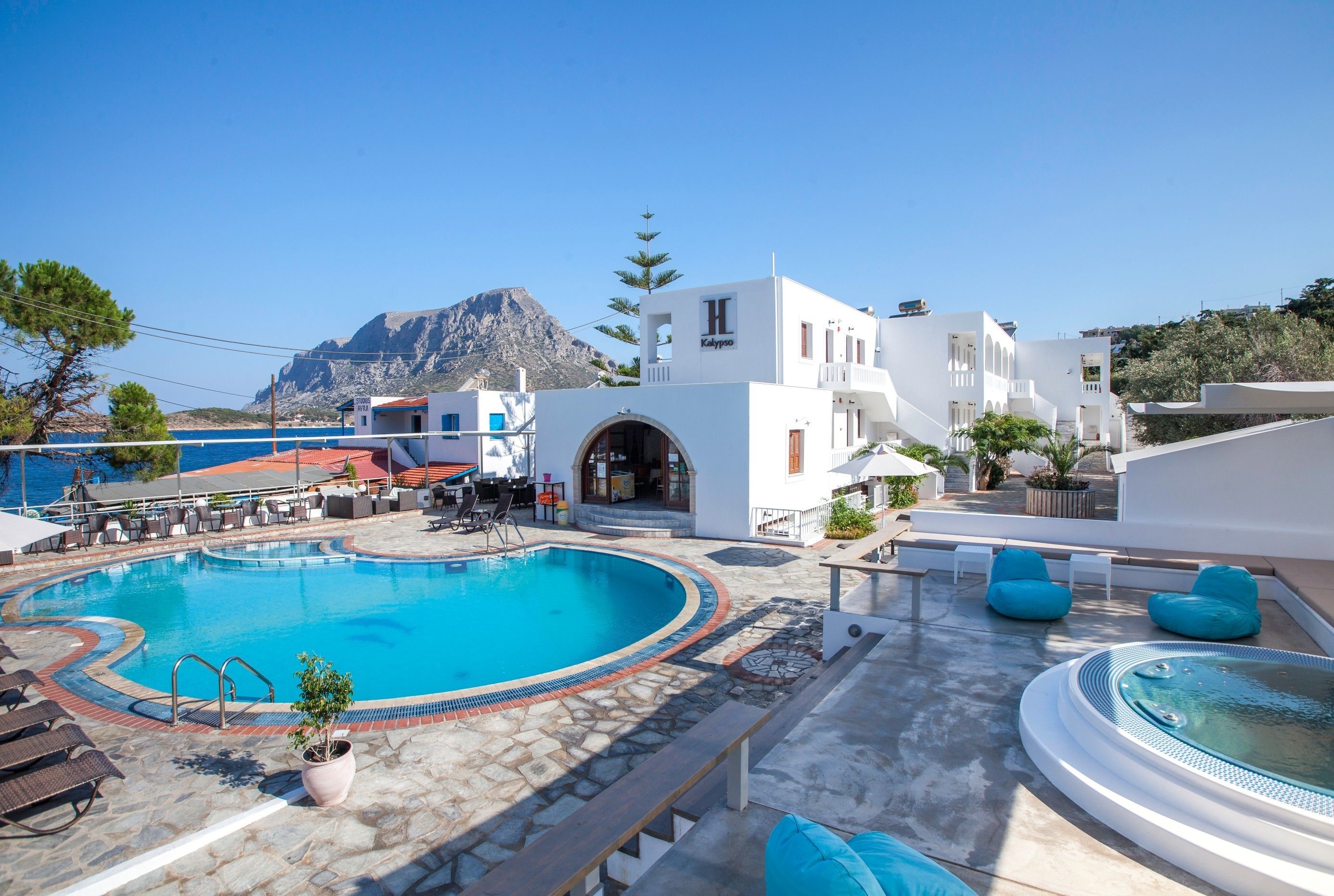 Uma piscina com deck de pedra, espreguiçadeiras e banheira de hidromassagem.