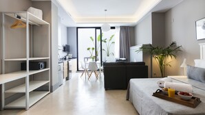Quarto de hotel moderno com cama, área de refeições, cozinha compacta e sala de estar.
